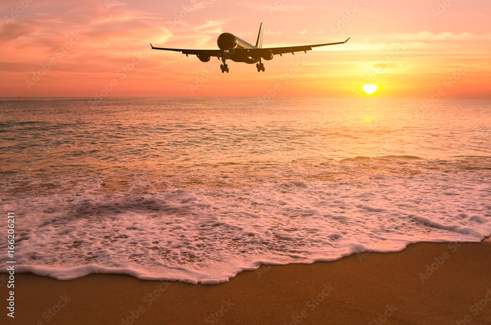 Airplane flying over tropical beach with smooth wave and sunset sky ...