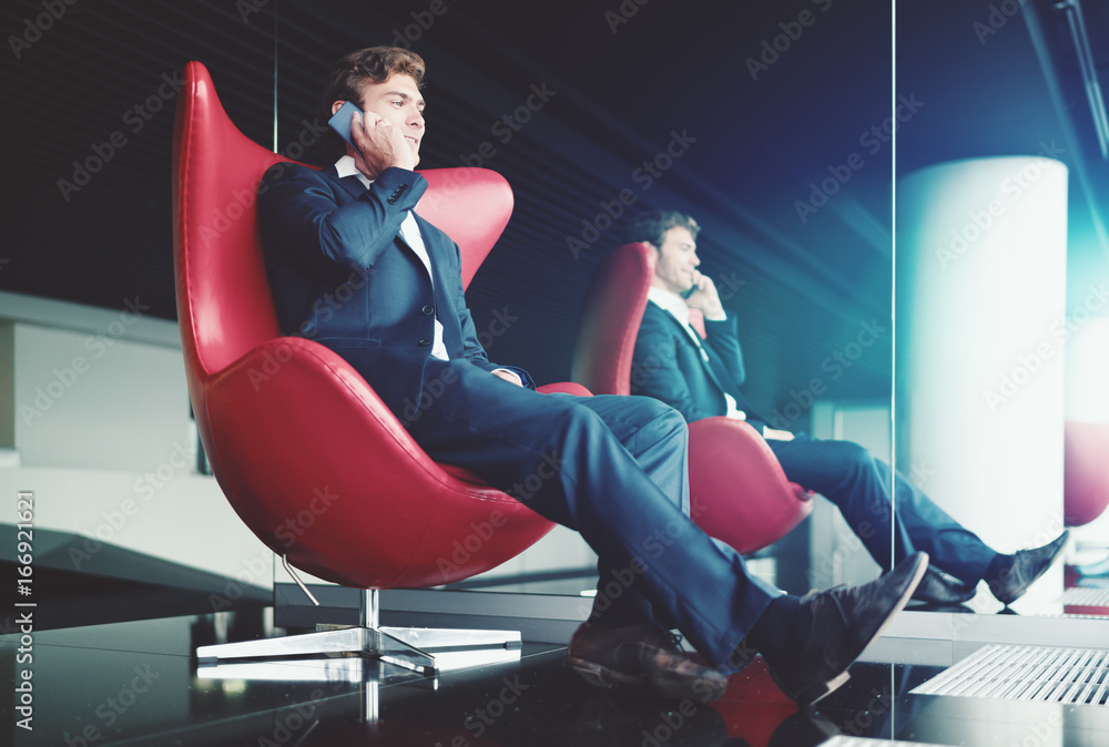 Smiling businessman in formal suit is sitting relaxed in chillout area ...
