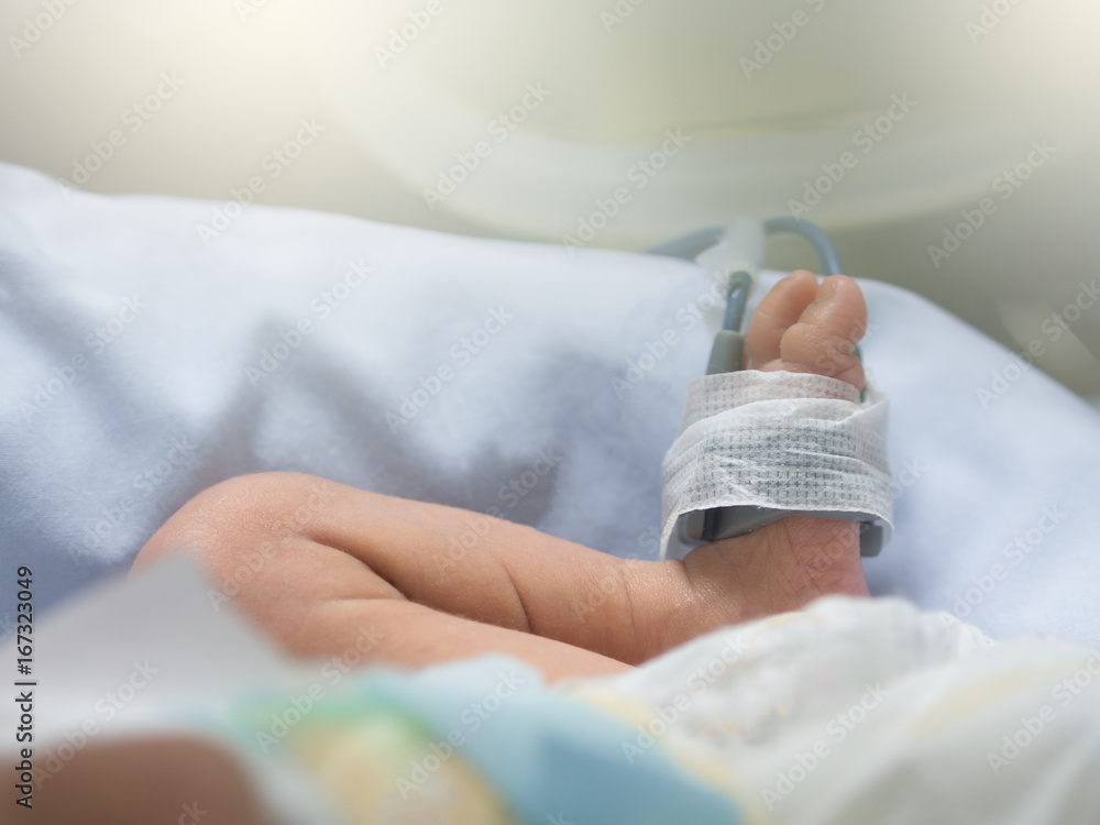 Newborn baby feet and leg with oxygen saturation monitor or pulse ...