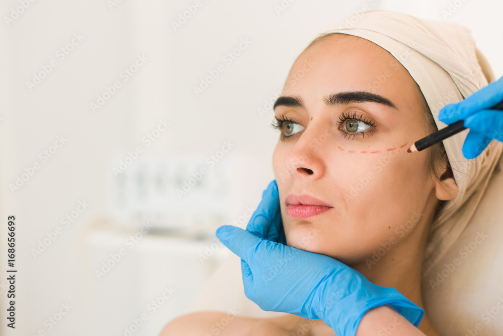 Doctor drawing marks on female face against white background. Stock ...