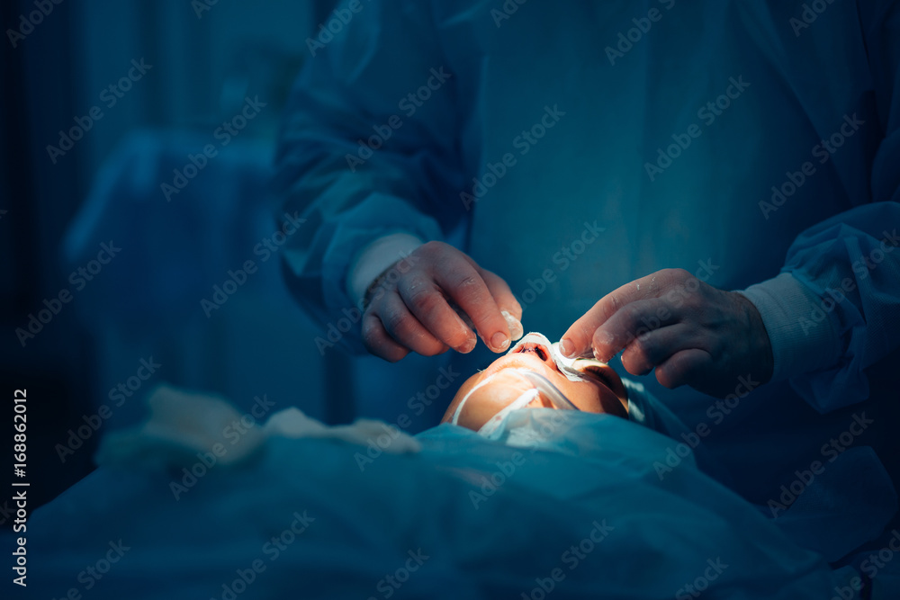 Surgeon wearing gloves operates women's nose . Operation close up ...