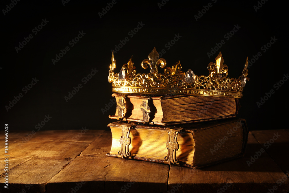 low key of beautiful queen/king crown on old books. vintage filtered ...