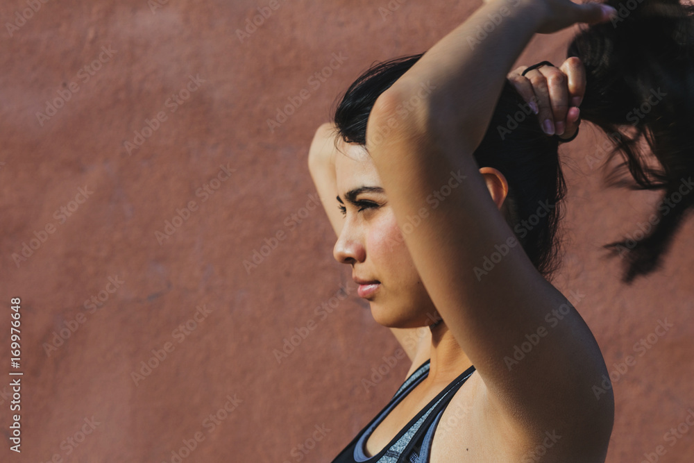 Latina woman pulling hair into a ponytail Stock Photo | Adobe Stock