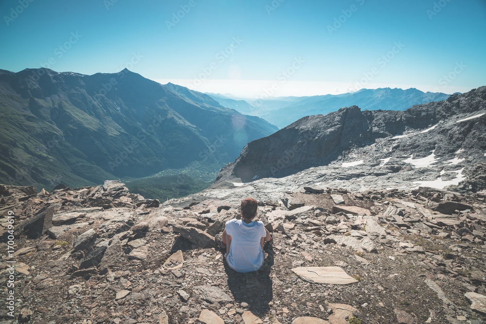 One person sitting on rocky terrain and watching a colorful sunrise ...