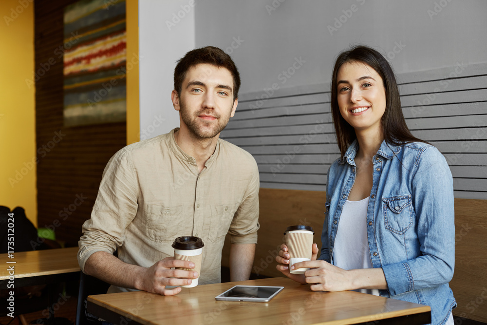 Two beautiful young students sitting in cafeteria, drinking cocoa ...