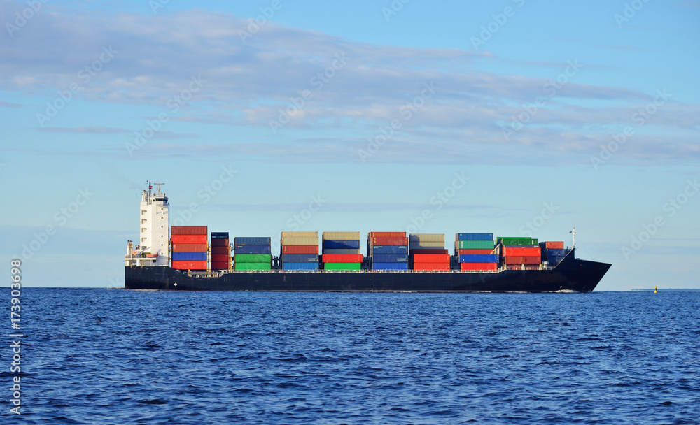 Black container ship sailing in calm water near port of Riga Stock ...