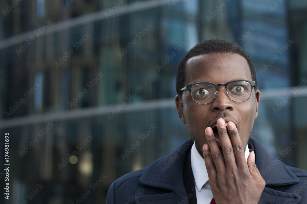 Astonished bug-eyed dark-skinned businessman wearing suit, covering his ...