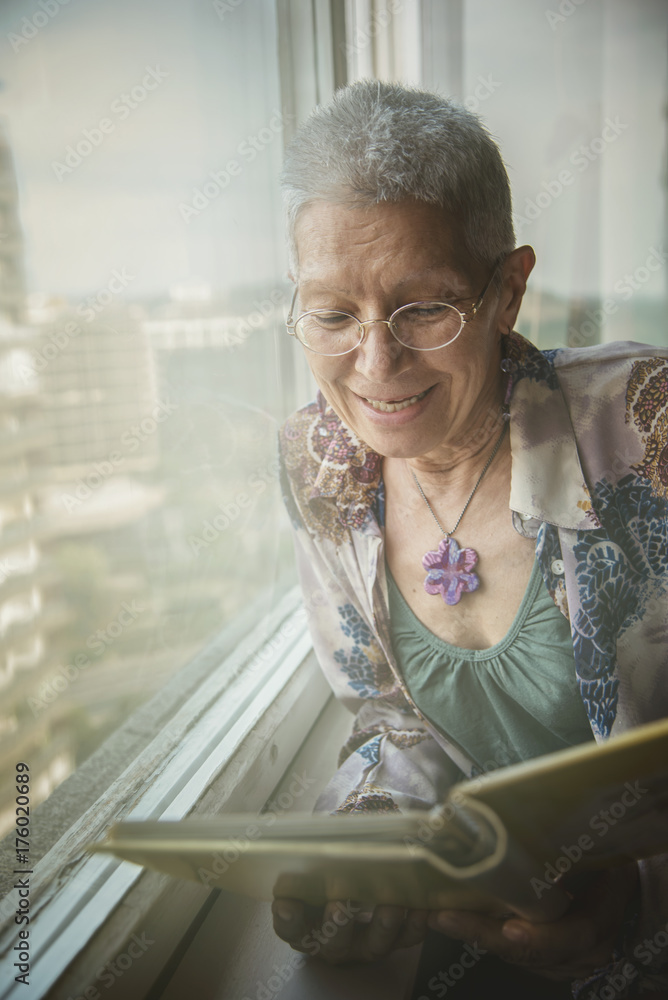 ภาพถ่าย Stock Senior elderly lady looking at some old photos in a photo ...