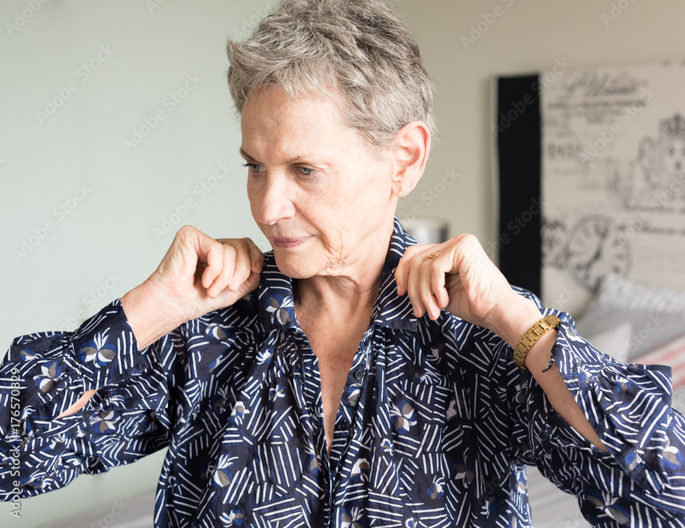 Head and shoulders view of older woman adjusting collar while getting ...