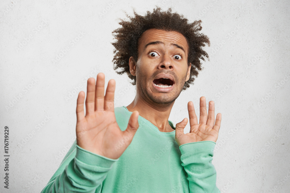 Scared terrified worried male keeps palms in front, exclaims loudly ...