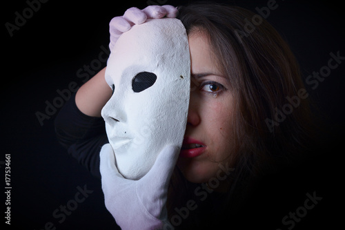 brunette girl is holding a theater mask in front of their face Stock ...
