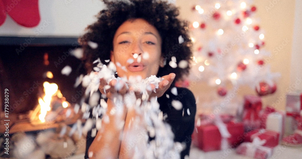 Adorable sexy woman blowing out confetti from her hands into camera ...