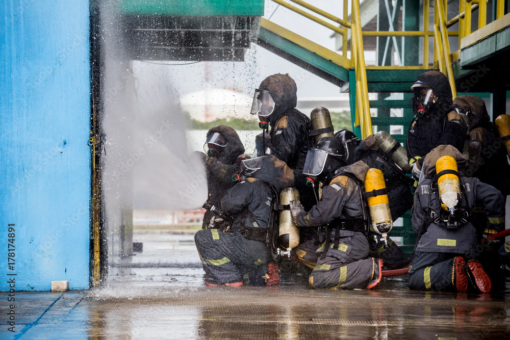 Firemen using water from hose for fire fighting at firefight training ...