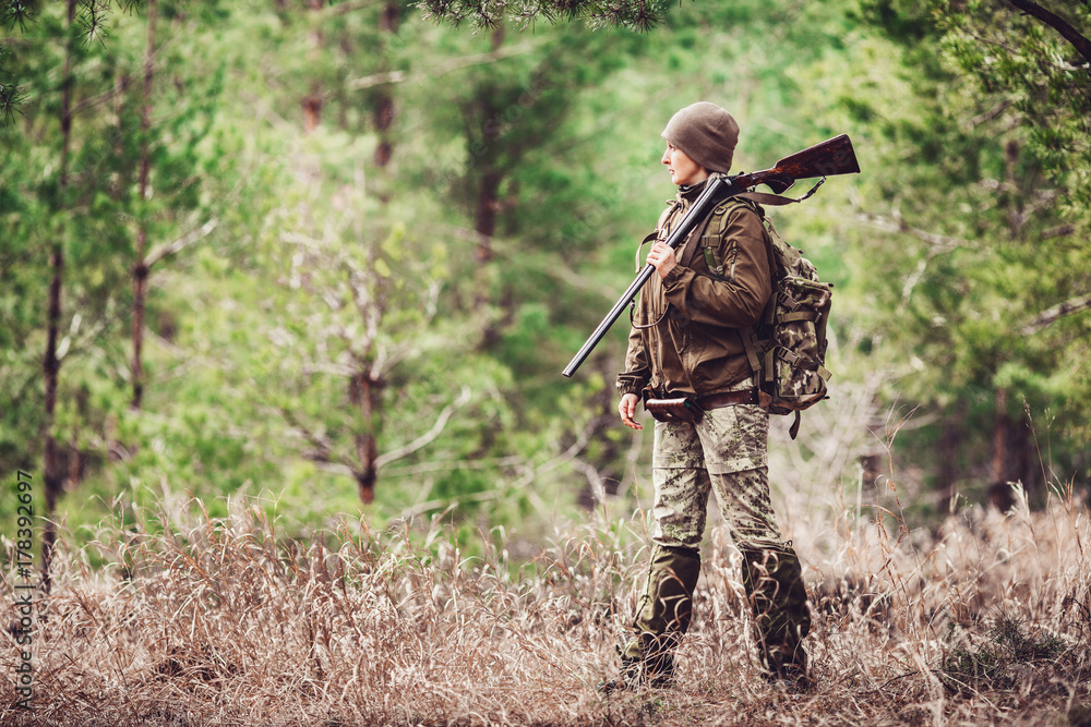 Female hunter in camouflage clothes ready to hunt, holding gun and ...