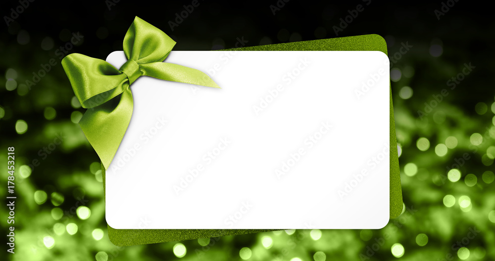 greeting gift card with green ribbon bow isolated on blurred christmas ...