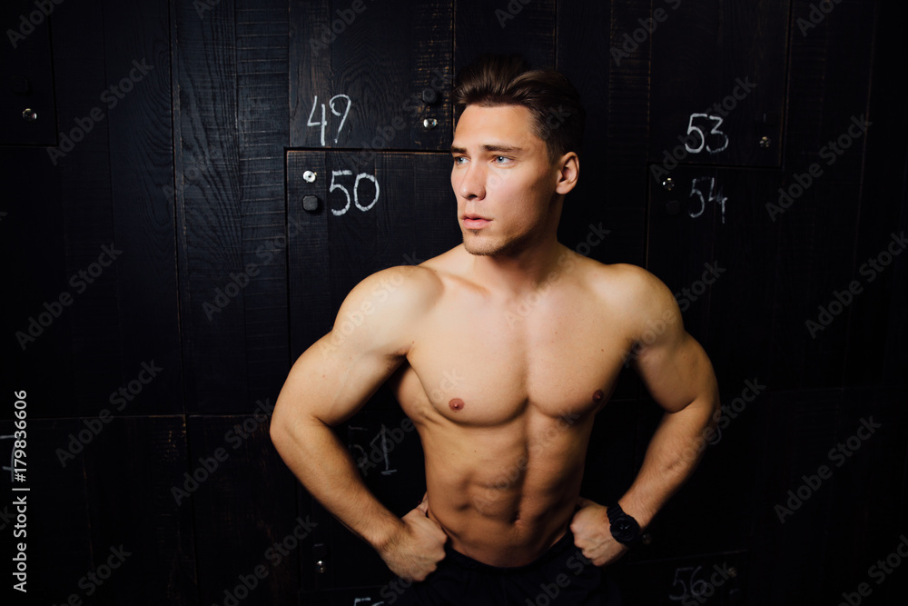 Portrait of fitness model handsome man , torso in locker room. Portrait before or after workout ...
