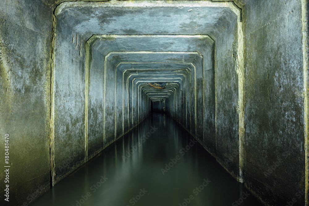 Dark and creepy flooded underground sewer concrete tunnel. Industrial ...