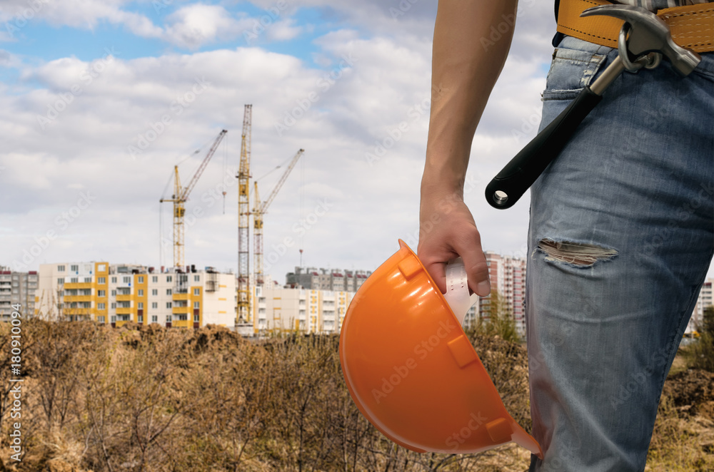 Builder worker with hummer on mounting belt holding in hands a hardhat ...
