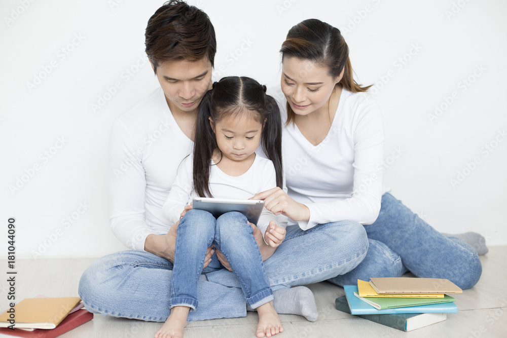 Little Girl using tablet with dad and mon together at home. People with ...