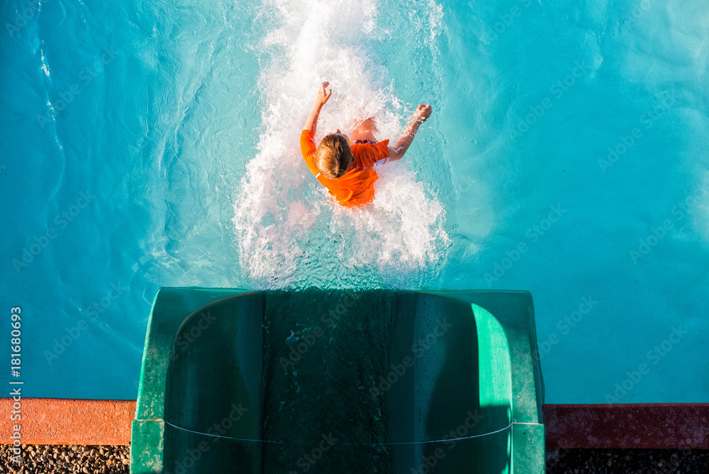 Photo Stock Child exiting a water slide into a swimming pool | Adobe Stock