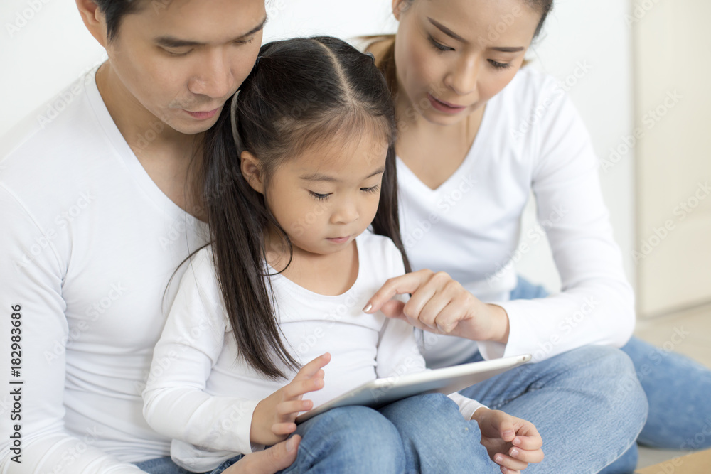 Little Girl using tablet with dad and mon together at home. People with ...