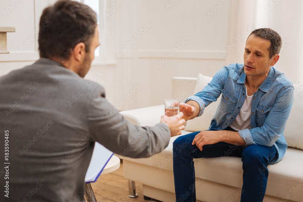 Calm down. Frustrated troubled male patient sitting on the sofa and ...