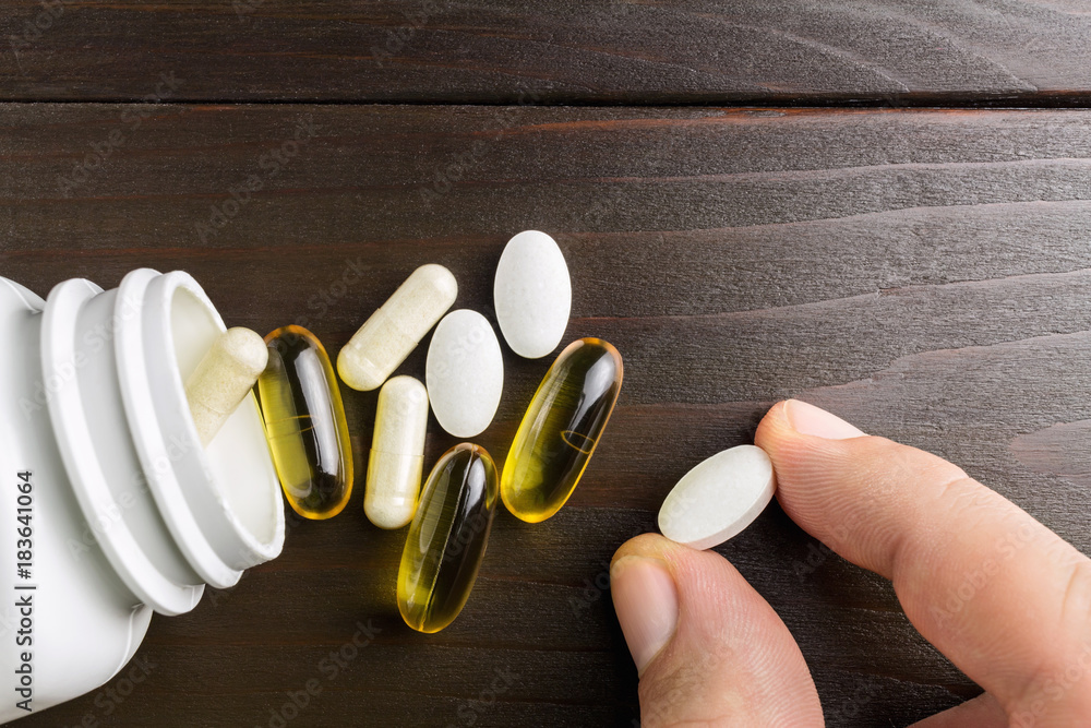 Photo Stock Hand takes white calcium pills, complex of vitamins and ...