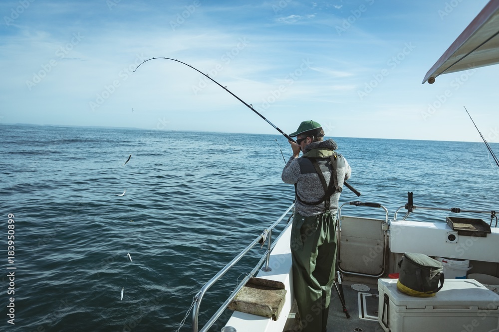 Fisherman fishing from the boat Stock Photo | Adobe Stock