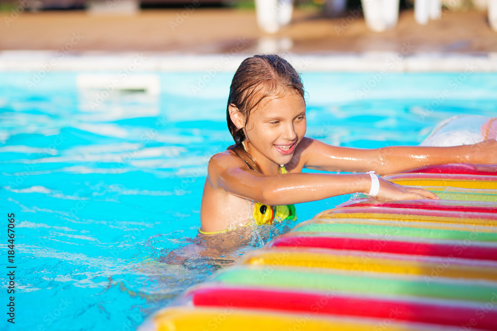 Little girl playing and having fun in swimming pool with air mattress ...