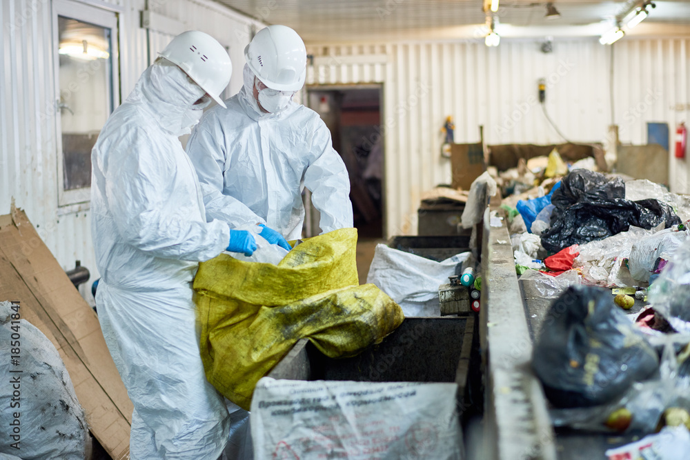 Side view portrait of two workers wearing biohazard suits sorting ...