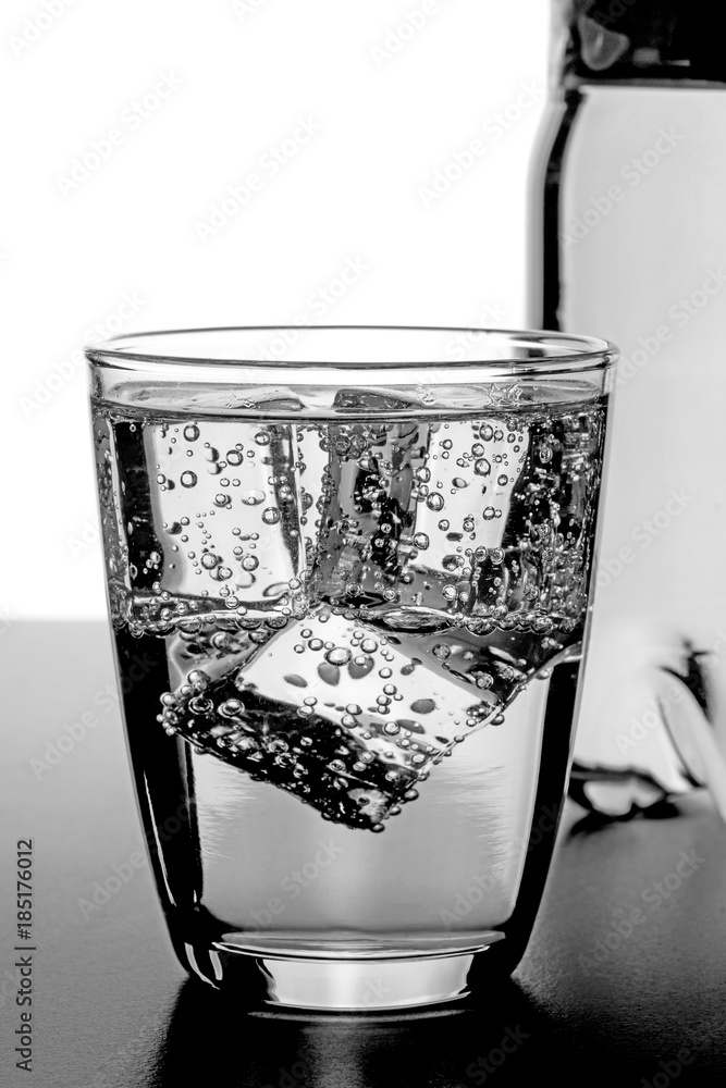 A glass of cold water with ice cubes and bottle in the background Stock ...