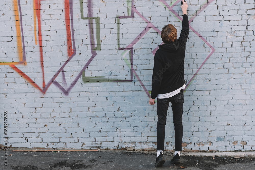 back view of man painting colorful graffiti on wall Stock Photo | Adobe ...