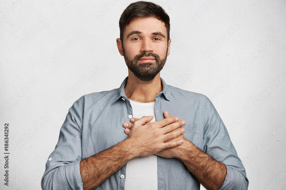 Pleased handsome male expresses his positive feeling to people who ...