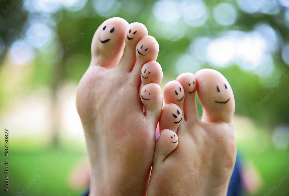 smiley faces on a pair of feet on all ten toes in a park on a hot ...