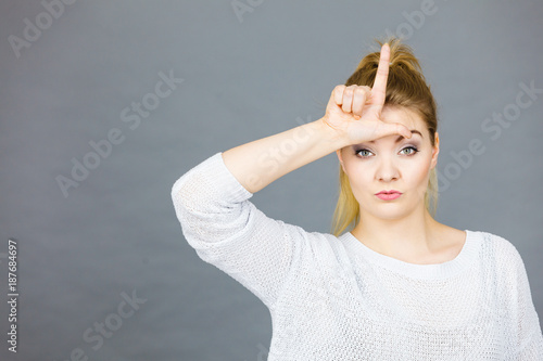 Woman showing loser gesture with L on forehead Stock Photo | Adobe Stock