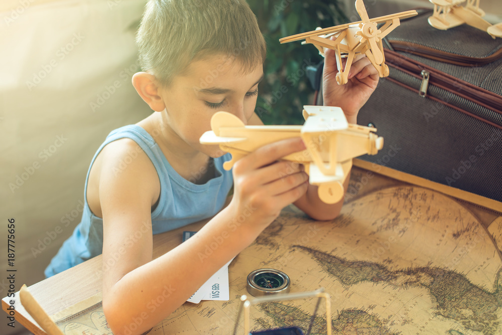 Boy child with toy airplanes in his hands, exploring the map to travel ...