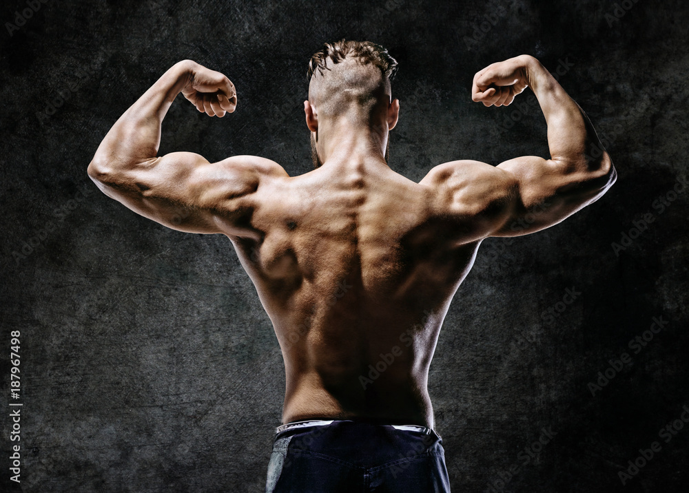 Muscular back of man flexing his arms. Rear view of fitness model with ...