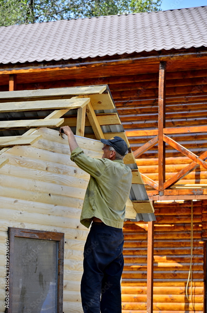 Carpenter checks the straight line before fastening metal roofing to ...