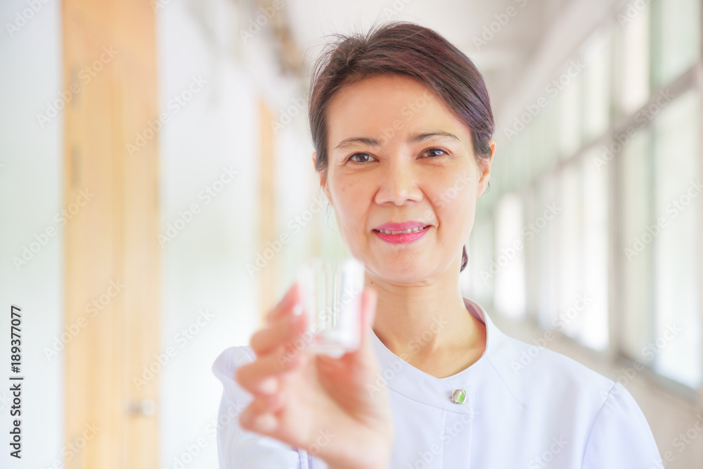 Smiling female nurse holding pill cup in her hands for patients ...