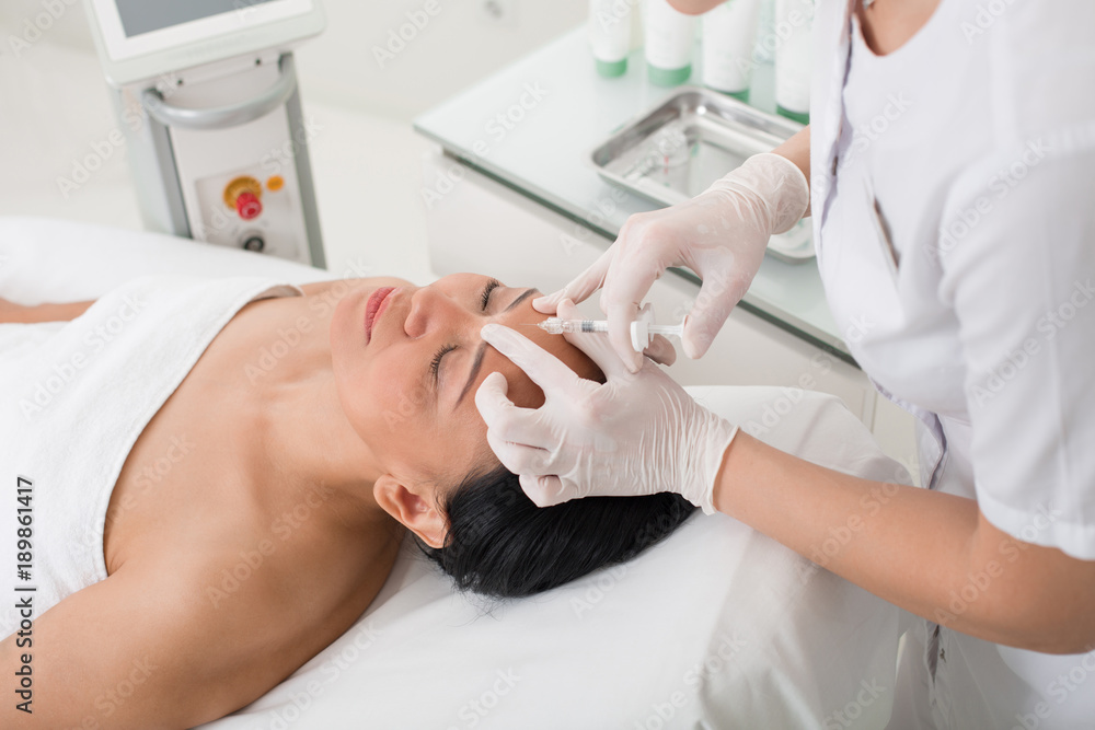 Serene middle-aged lady going for botox treatment in wellness center ...