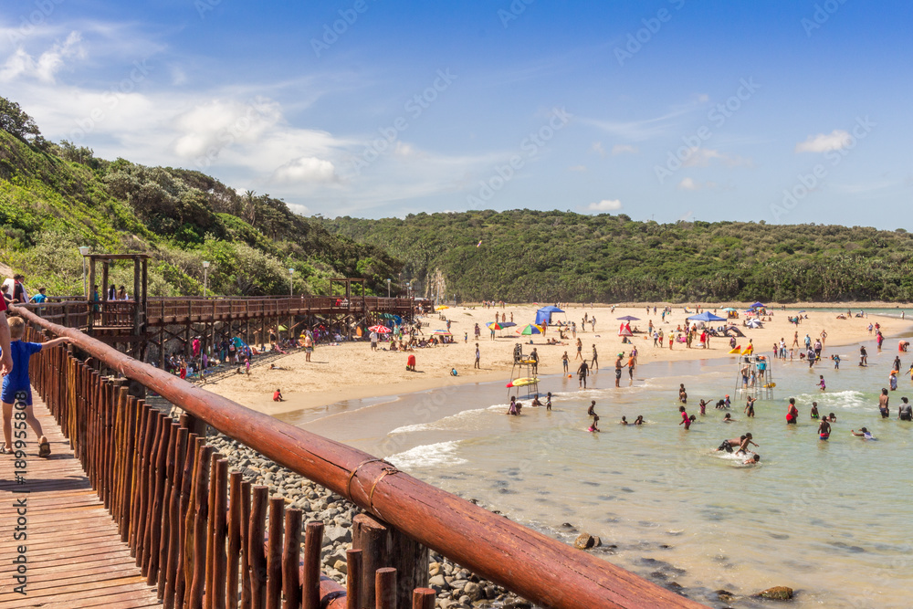 Beachgoers having fun on a hot summer day on the beach near a boardwalk ...