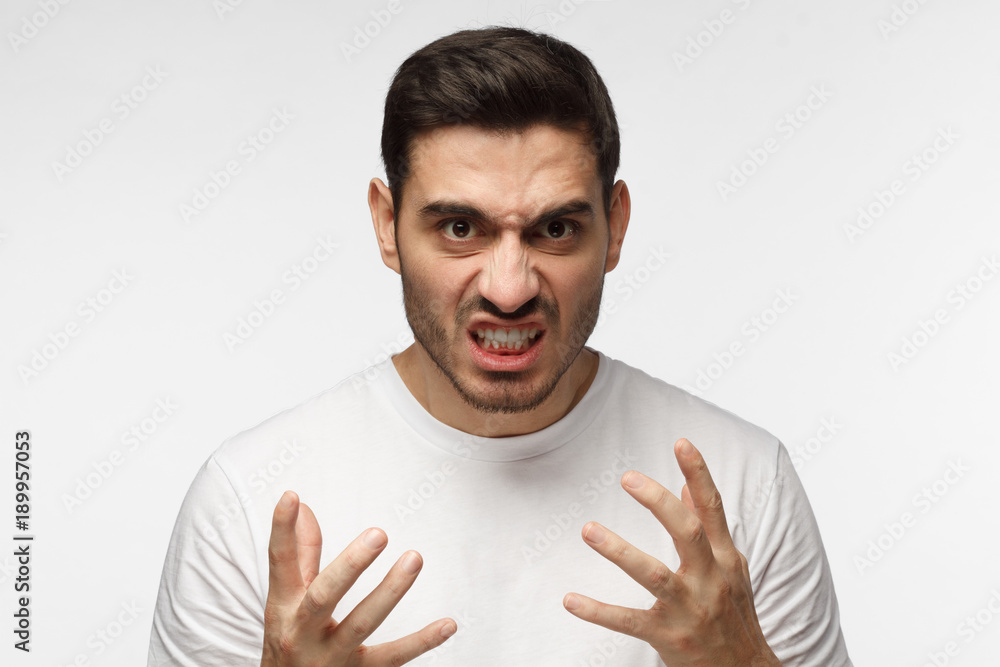 Shut up concept. Mad young man bite his teeth, gesturing with hands ...