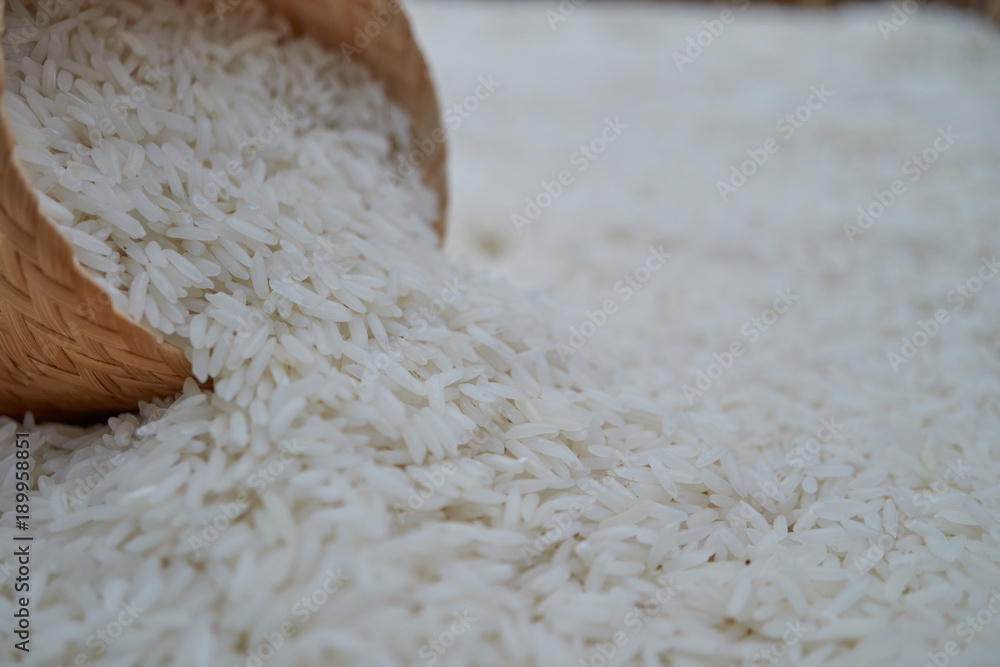 Close-up of grains of uncooked white jasmine rice in bamboo container ...