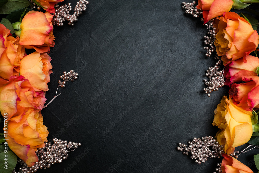 Orange and red autumn roses dark background with silver beads adornment ...