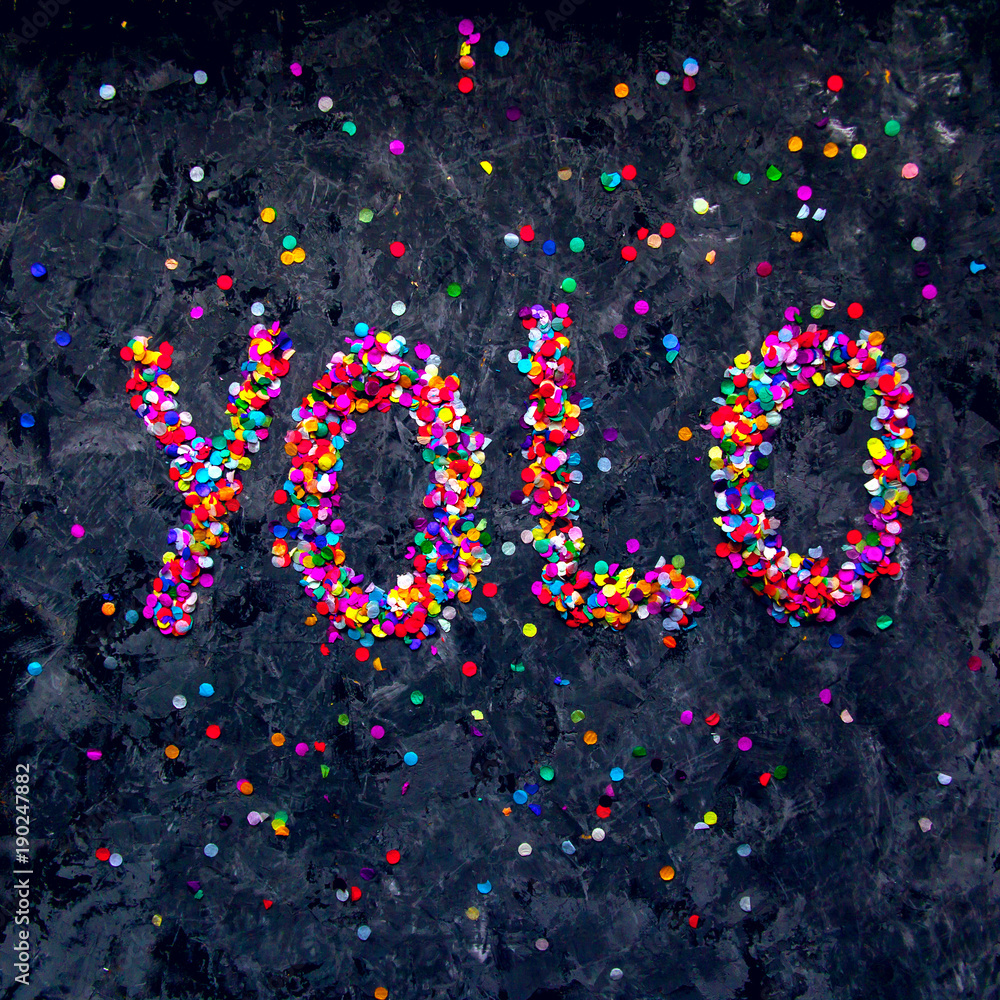 Word 'YOLO' made of colorful confetti on black textured background ...