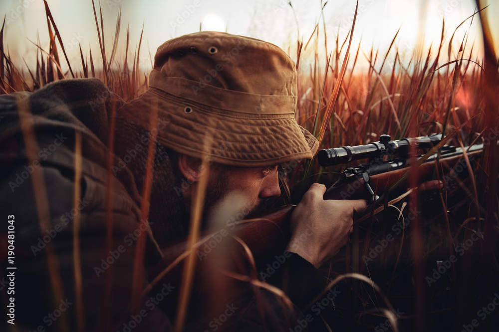 Hunter laying in long red grass looking trough his sniper Stock Photo ...