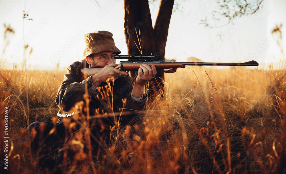 Hunter with sniper aiming prey hiding behind tree Stock Photo | Adobe Stock