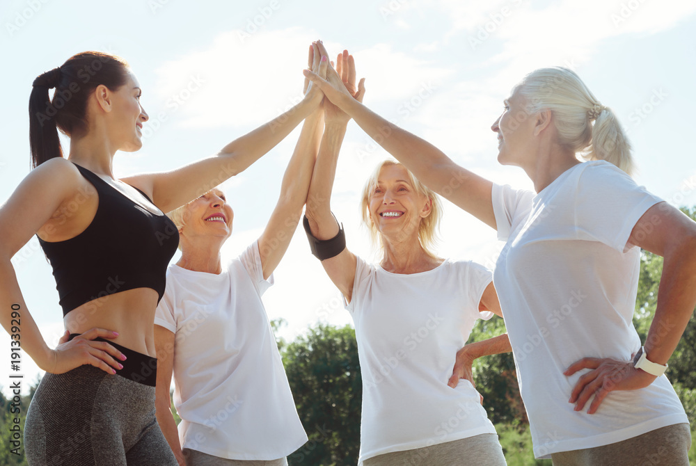 We are the team. Joyful nice active women looking at each other and ...