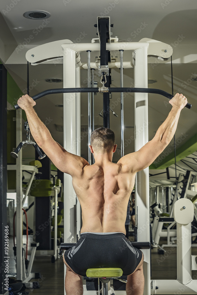 Shoulder pull down machine. Fitness man working out lat pulldown ...