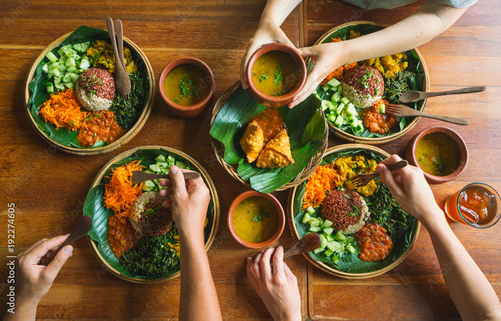 Vegetarian Indian food. several people eat Indian food at a common ...